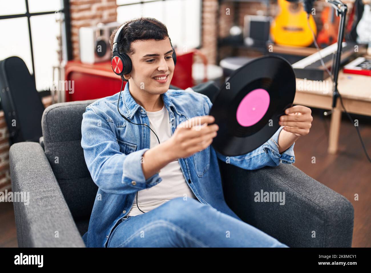 Young non binary man musician listening to music holding vinyl disc at ...