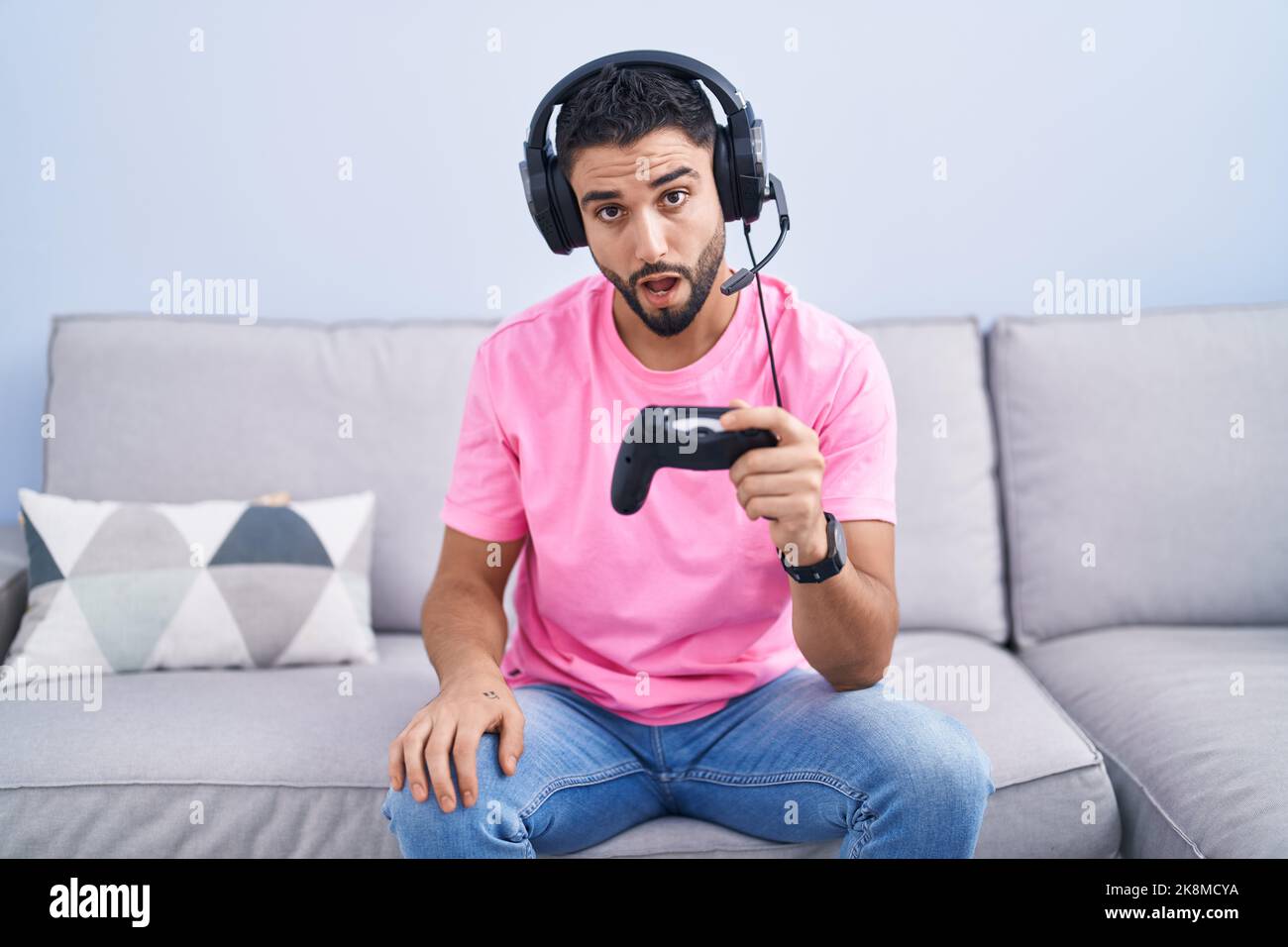 Hispanic young man playing video game holding controller sitting on the ...