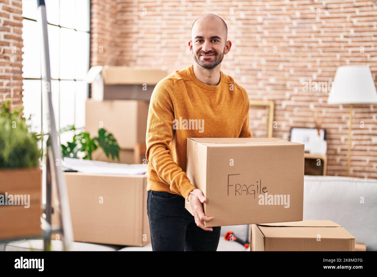 Young man smiling confident holding fragile cardboard box at new home Stock Photo - Alamy