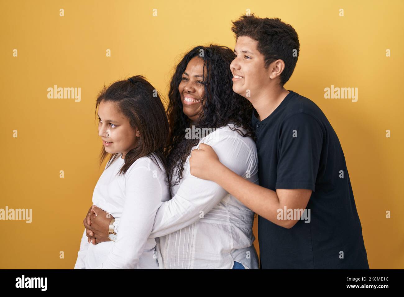 Family of mother, daughter and son standing over yellow background ...