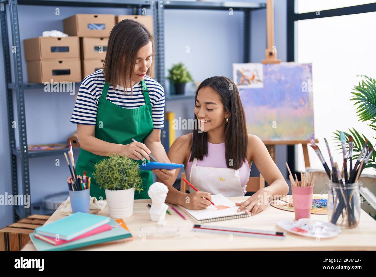 Two women artists using touchpad drawing on notebook at art studio ...