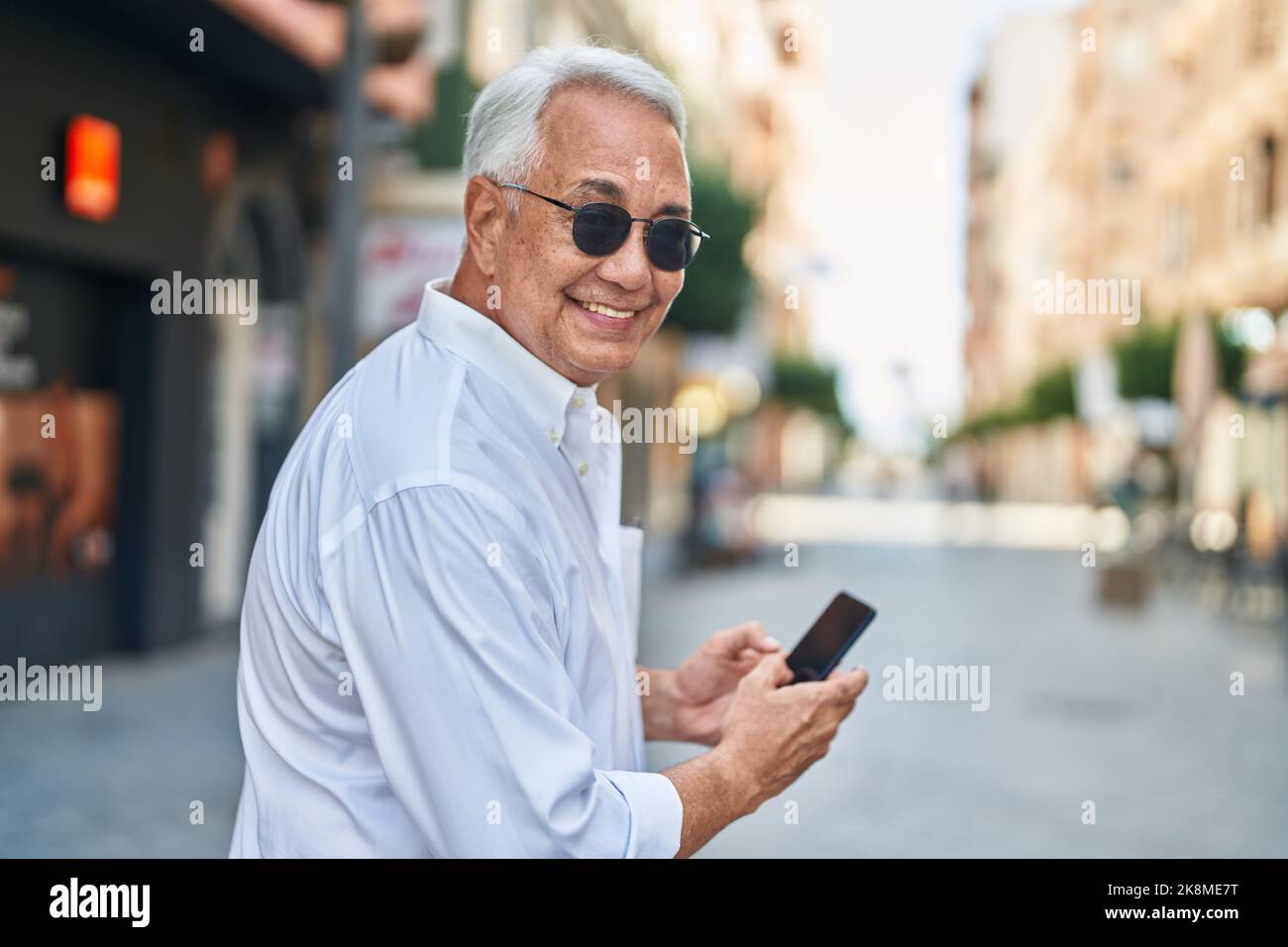 Middle age grey-haired man smiling confident using smartphone at street ...
