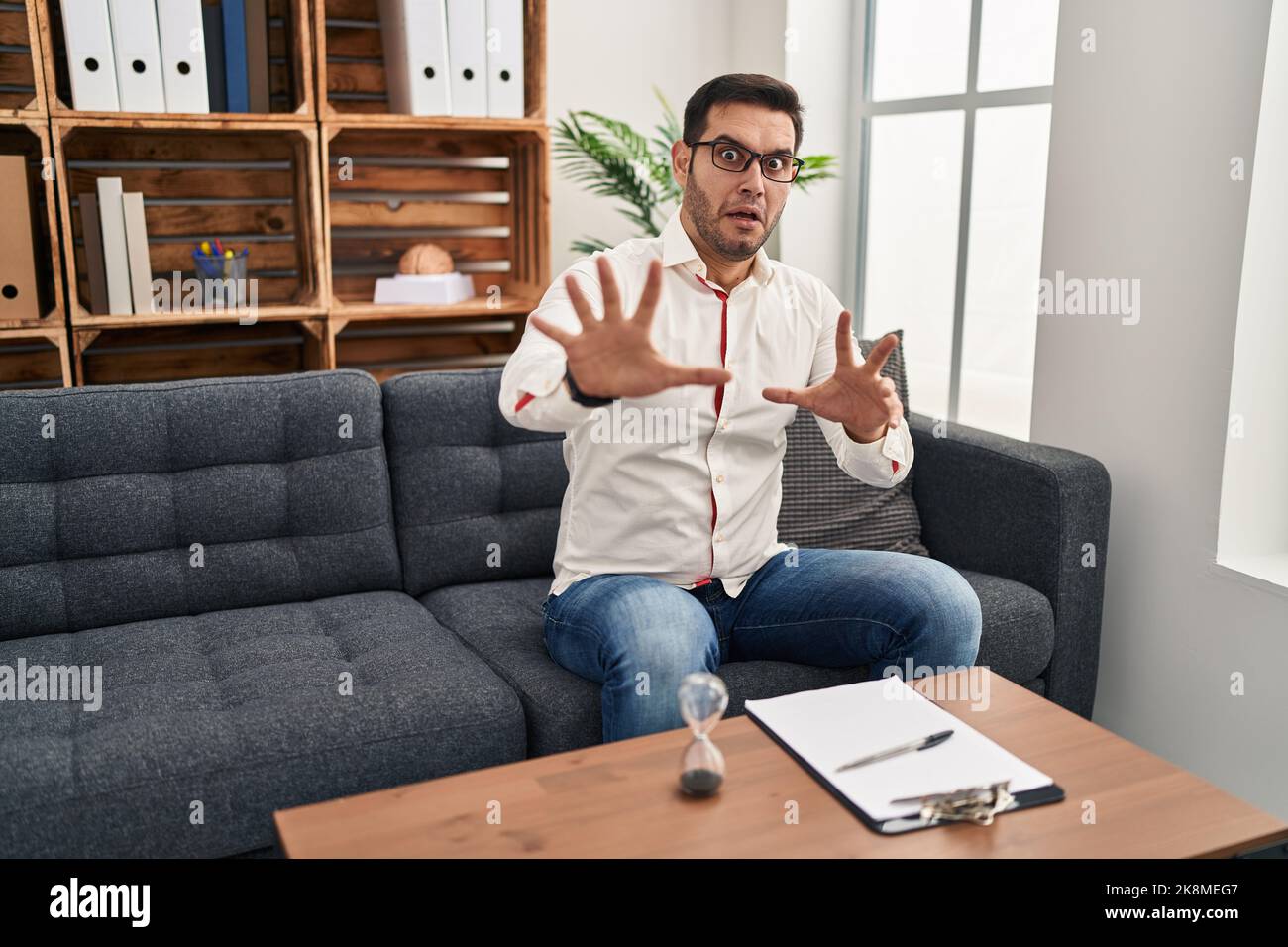 Young hispanic man with beard working at consultation office afraid and ...