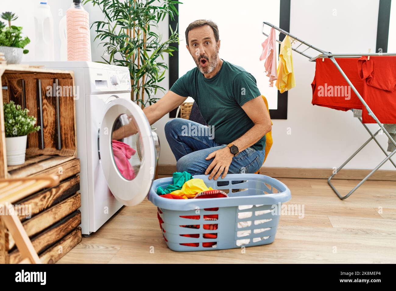 Middle age man with beard putting laundry in to washing machine scared ...