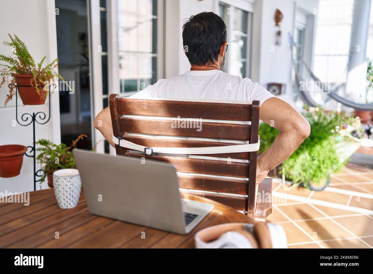 Middle age man using computer laptop at home standing backwards looking ...