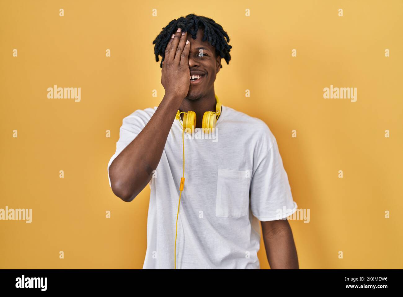 Young african man with dreadlocks standing over yellow background ...