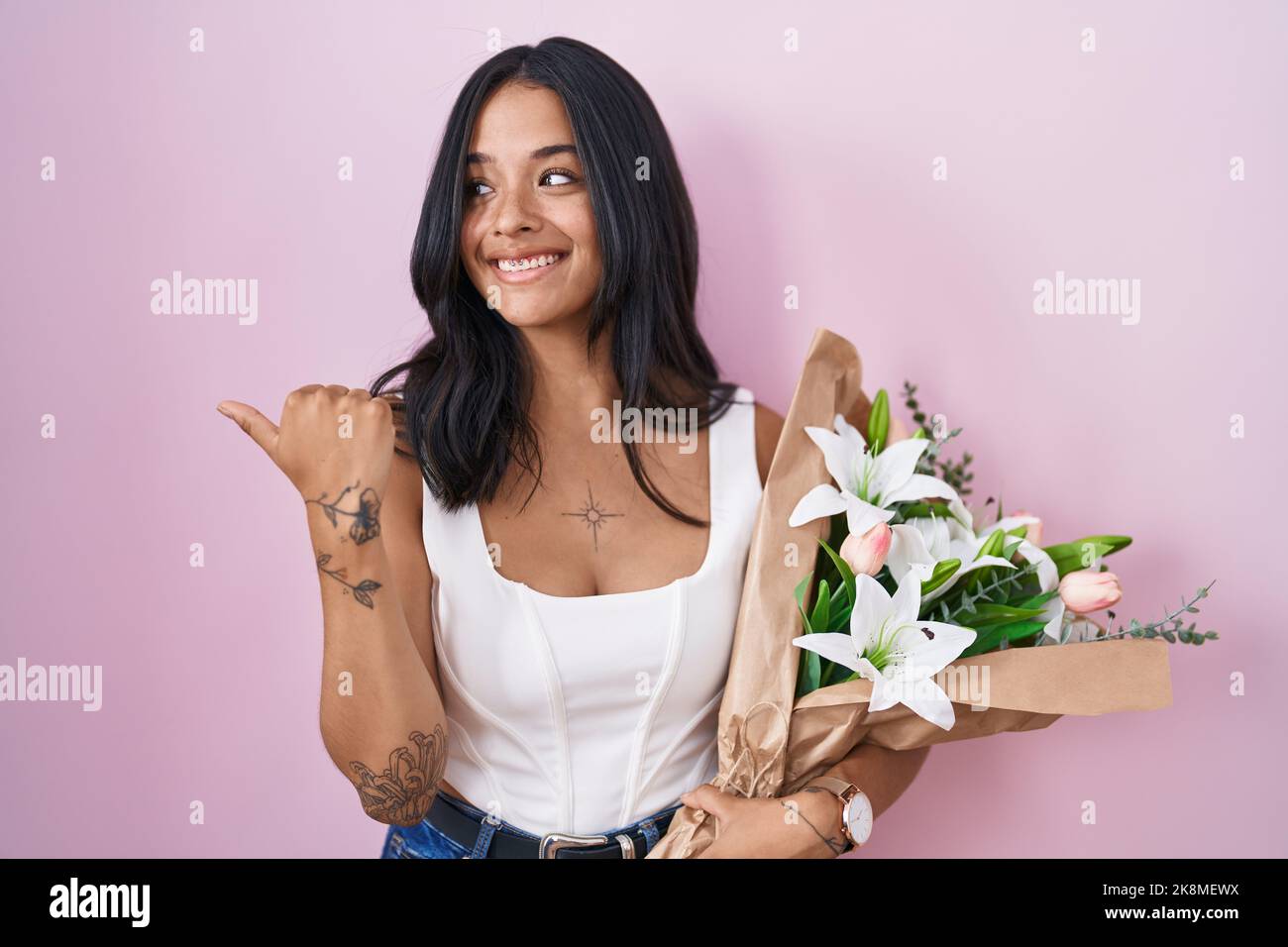 Brunette woman holding bouquet of white flowers smiling with happy face ...