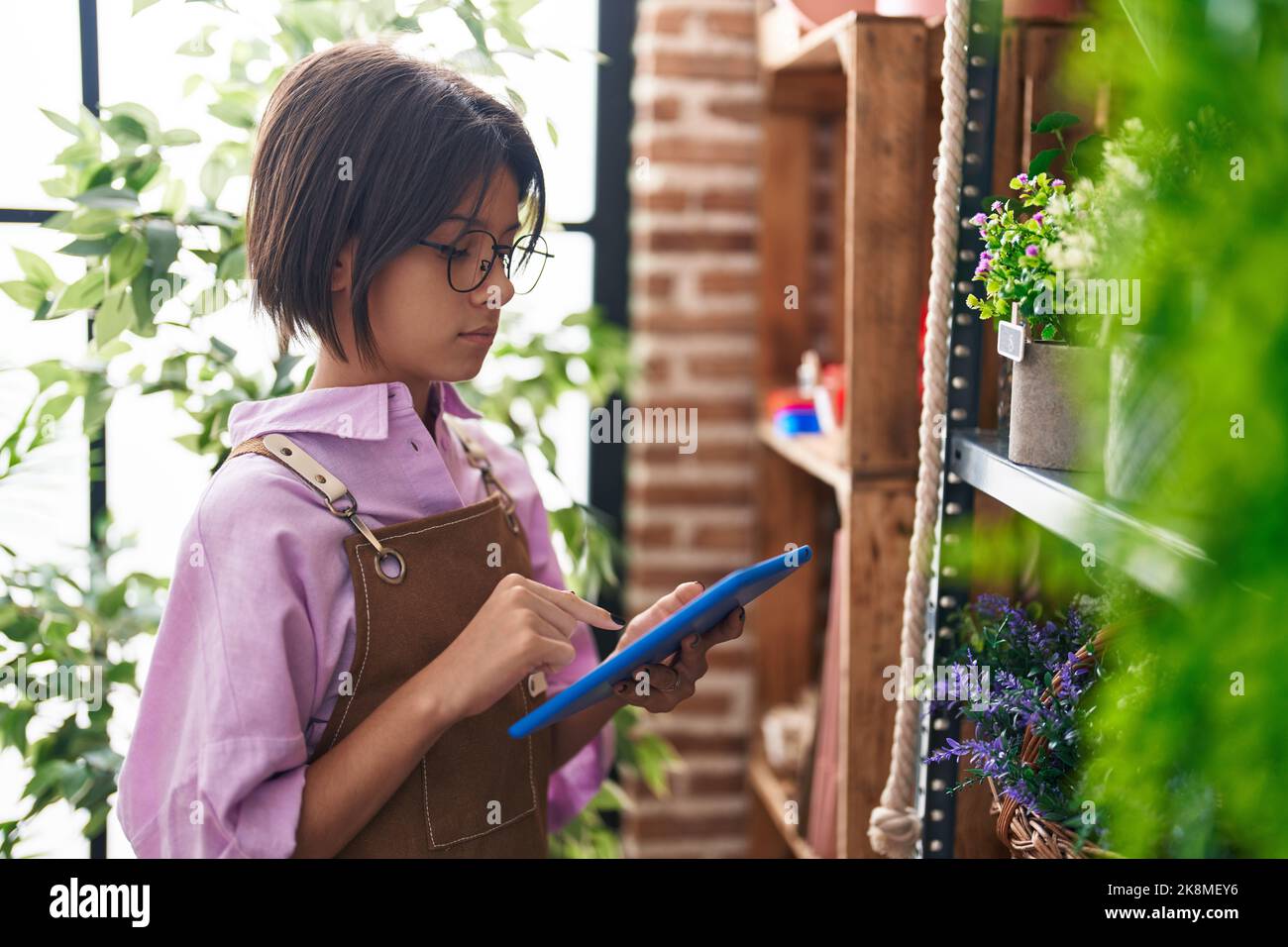 Adorable hispanic girl florist using touchpad at flower shop Stock ...