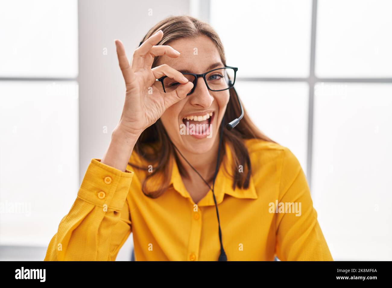 Young woman wearing call center agent headset smiling happy doing ok ...