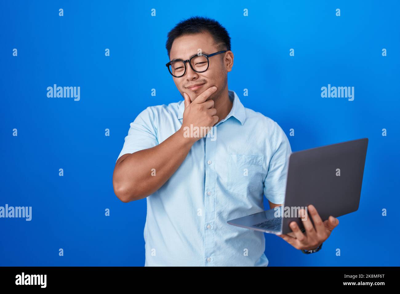 Chinese young man using computer laptop looking confident at the camera ...