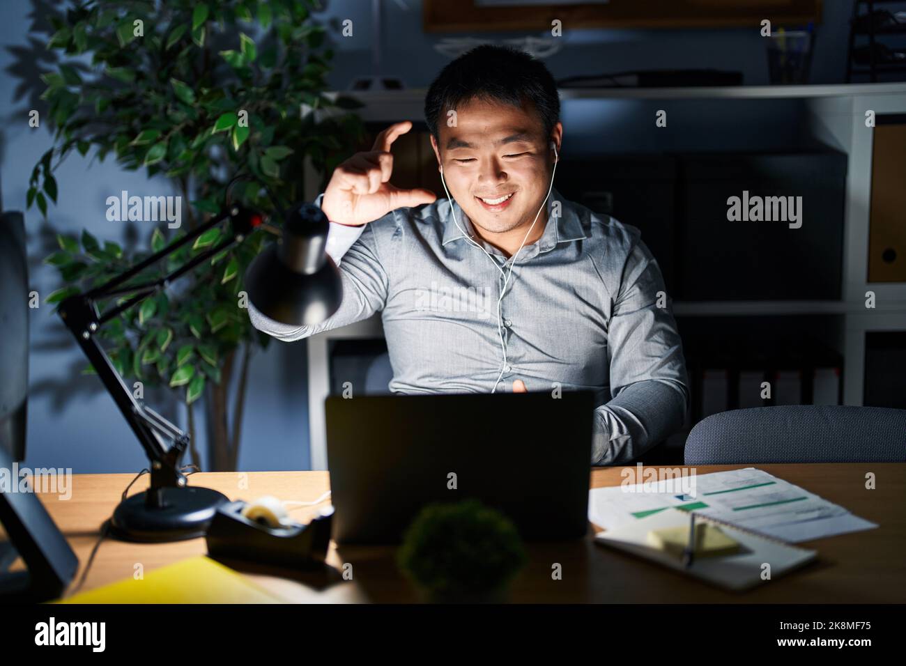 Young chinese man working using computer laptop at night smiling and ...