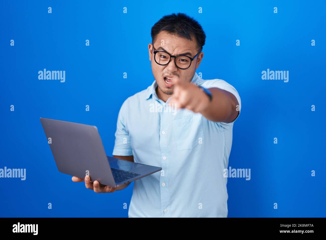 Chinese young man using computer laptop pointing displeased and ...