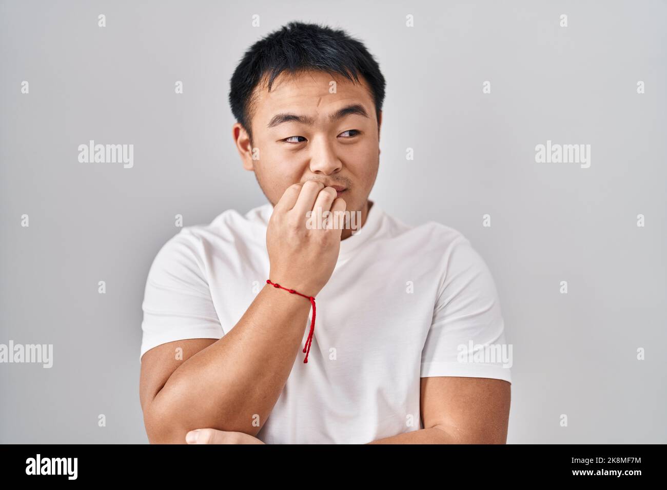 Young chinese man standing over white background looking stressed and ... Young chinese man standing over white background looking stressed and ...