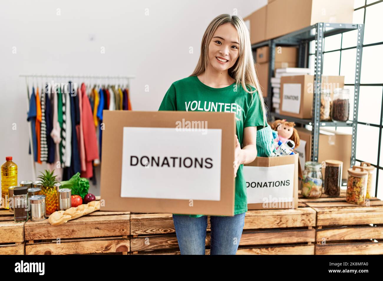 Young chinese woman wearing volunteer uniform holding donations box at ...