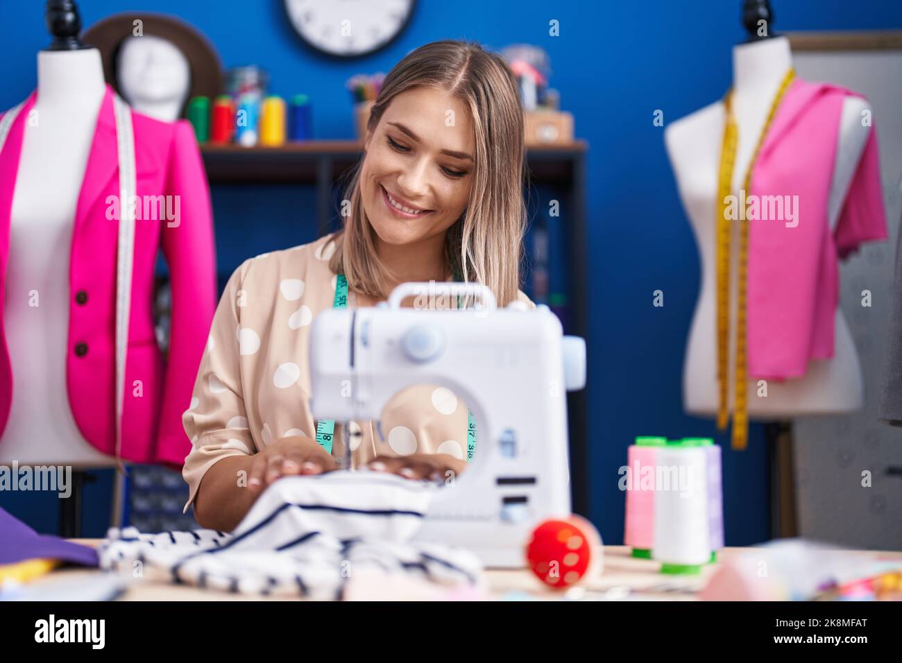 Young caucasian woman tailor smiling confident using sewing machine at ...