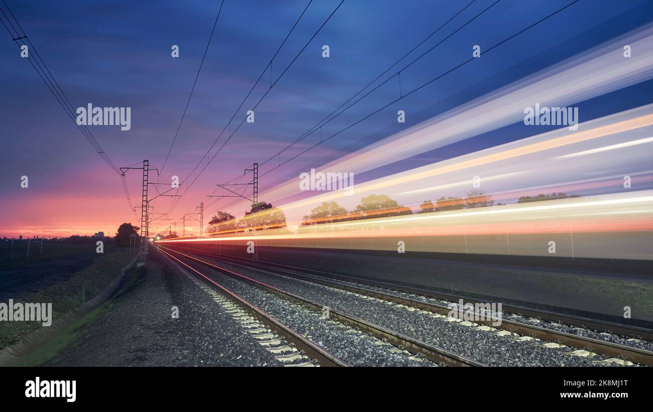 Modern railway at beautiful sunrise. Light trail of high speed train on ...