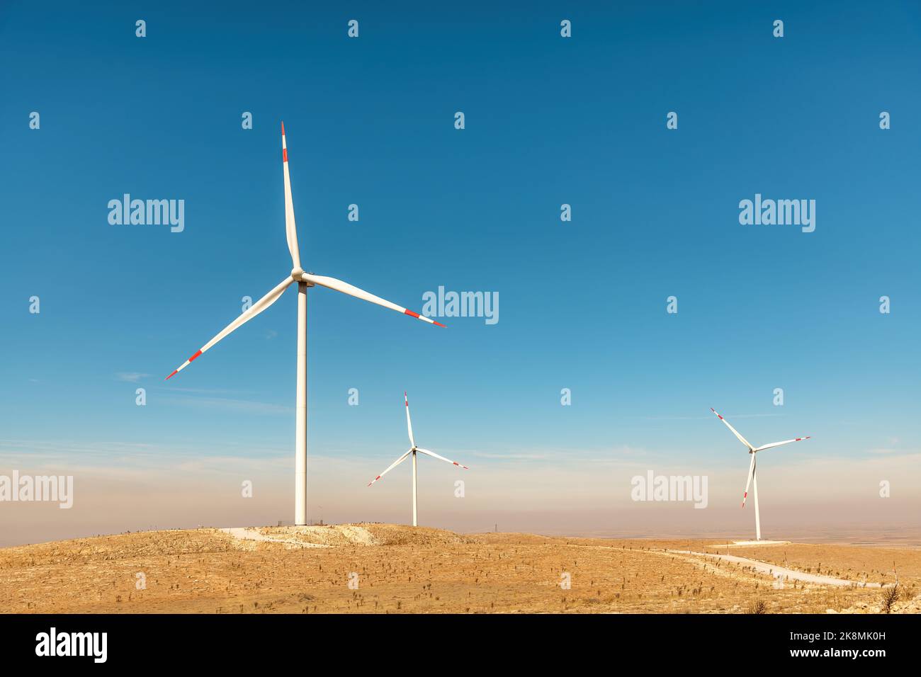 Multiple wind turbines standing on a hill at sunset and generating ...