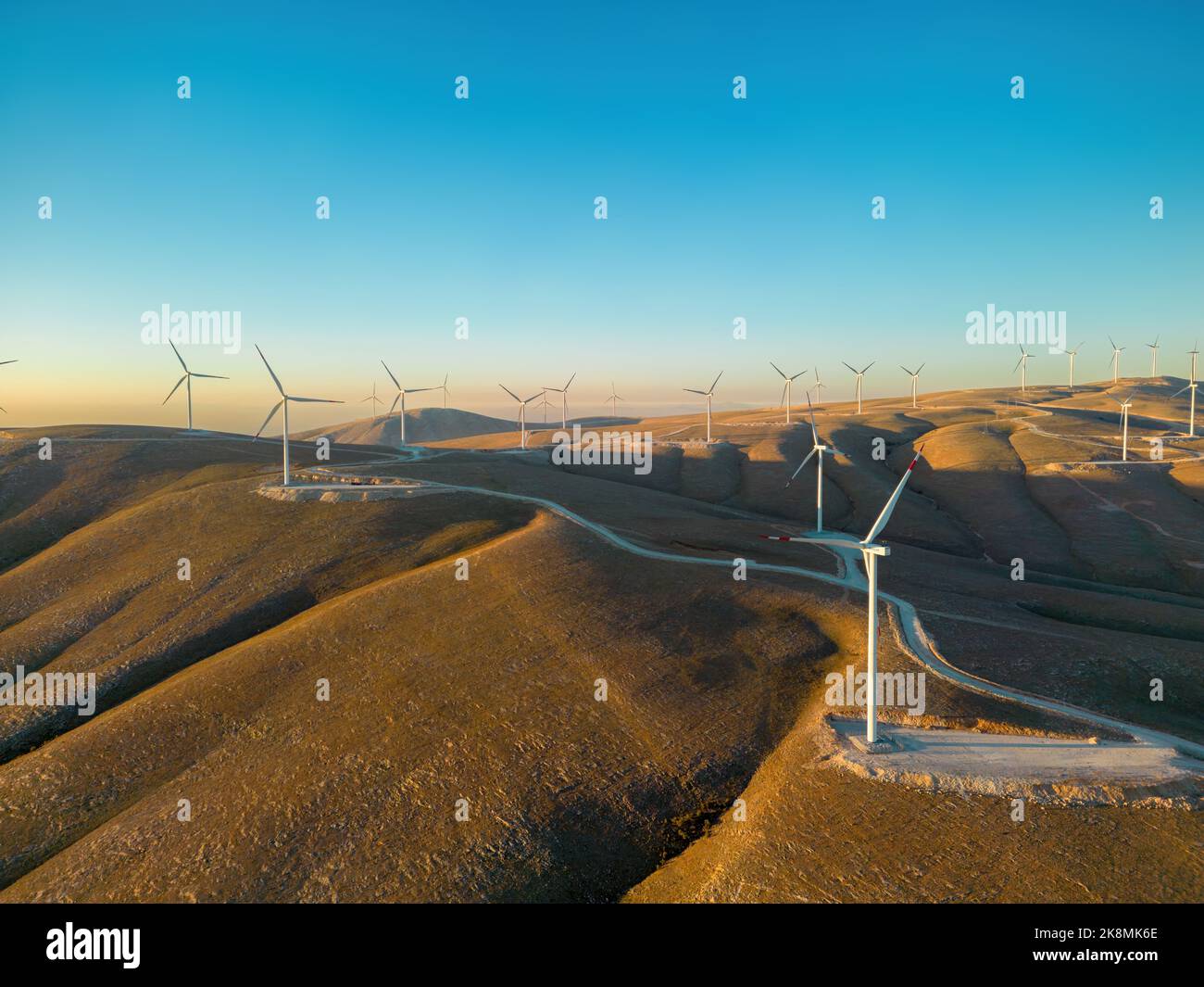 Aerial view of multiple wind turbines standing on a hill and generating ...
