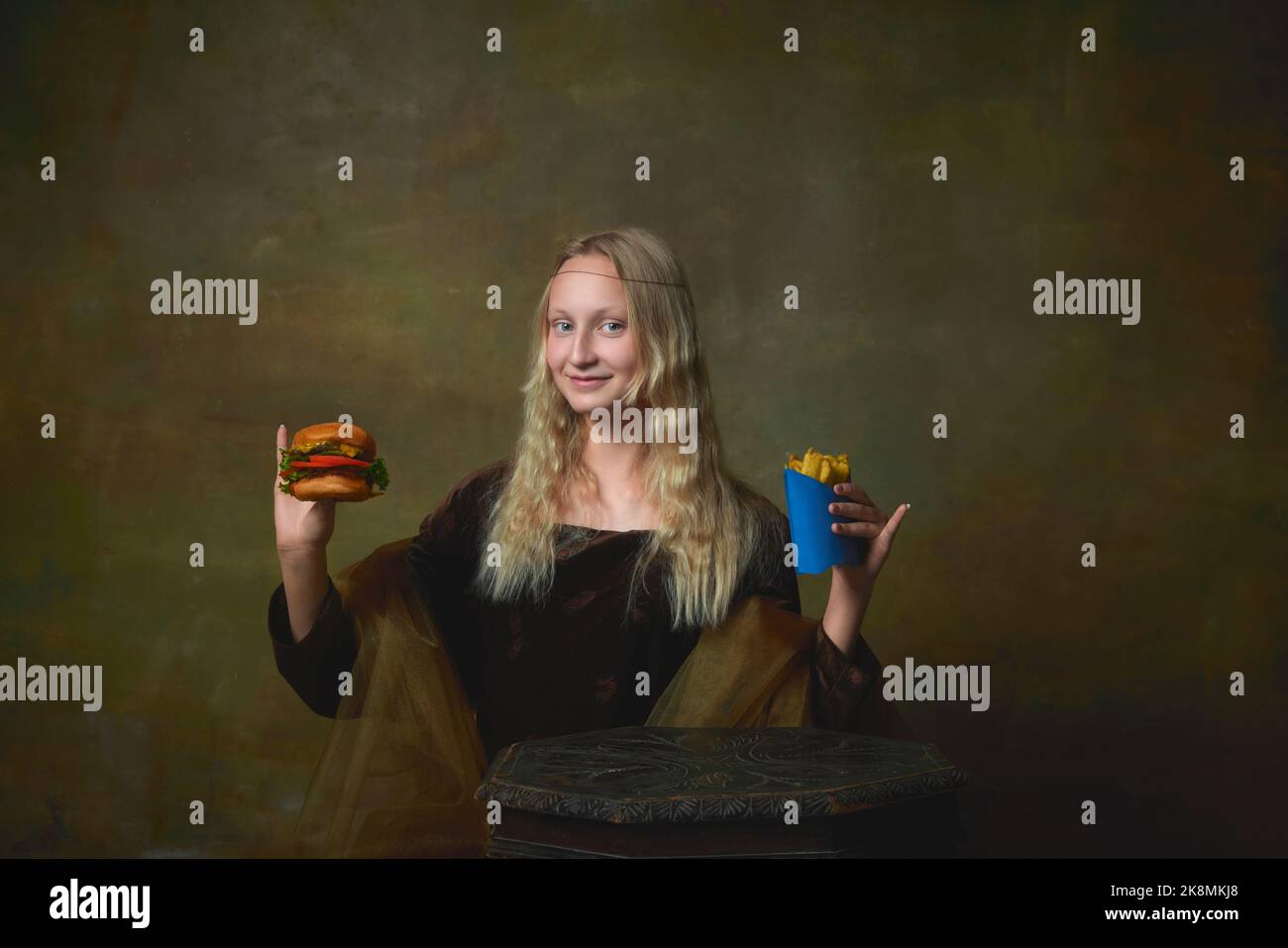 Fast food. Happy young girl as Mona Lisa picture holding hamburger over ...