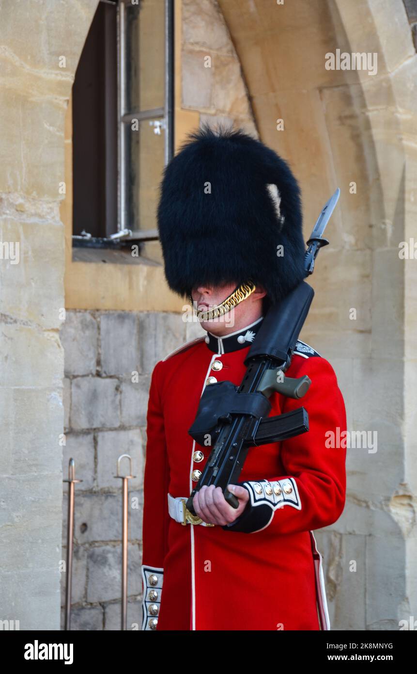 A vertical shot of a british guard carrying a weapon, with a red ...
