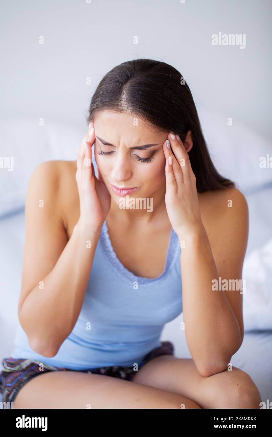 Head pain. Attractive young woman wake up on her bed looking unhappy and feeling sick Stock ...