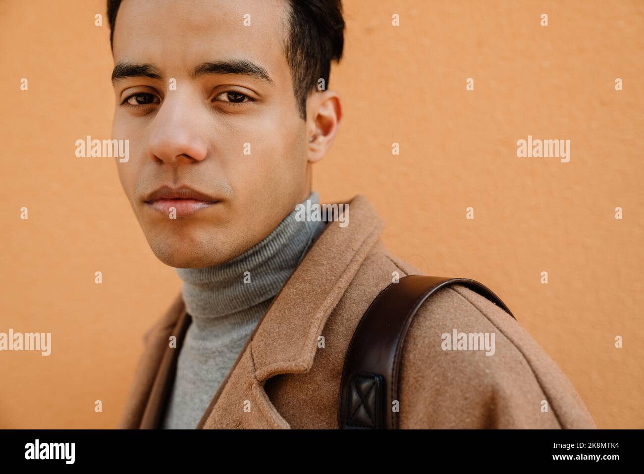 Young middle eastern man wearing coat standing by wall outdoors Stock ...
