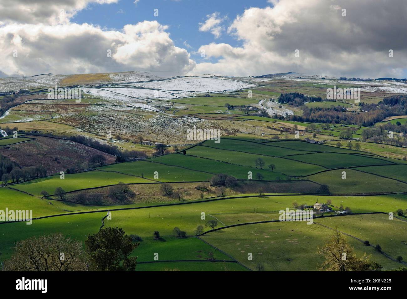 Birds-eye view looking into a valley of green fields with a steep ...