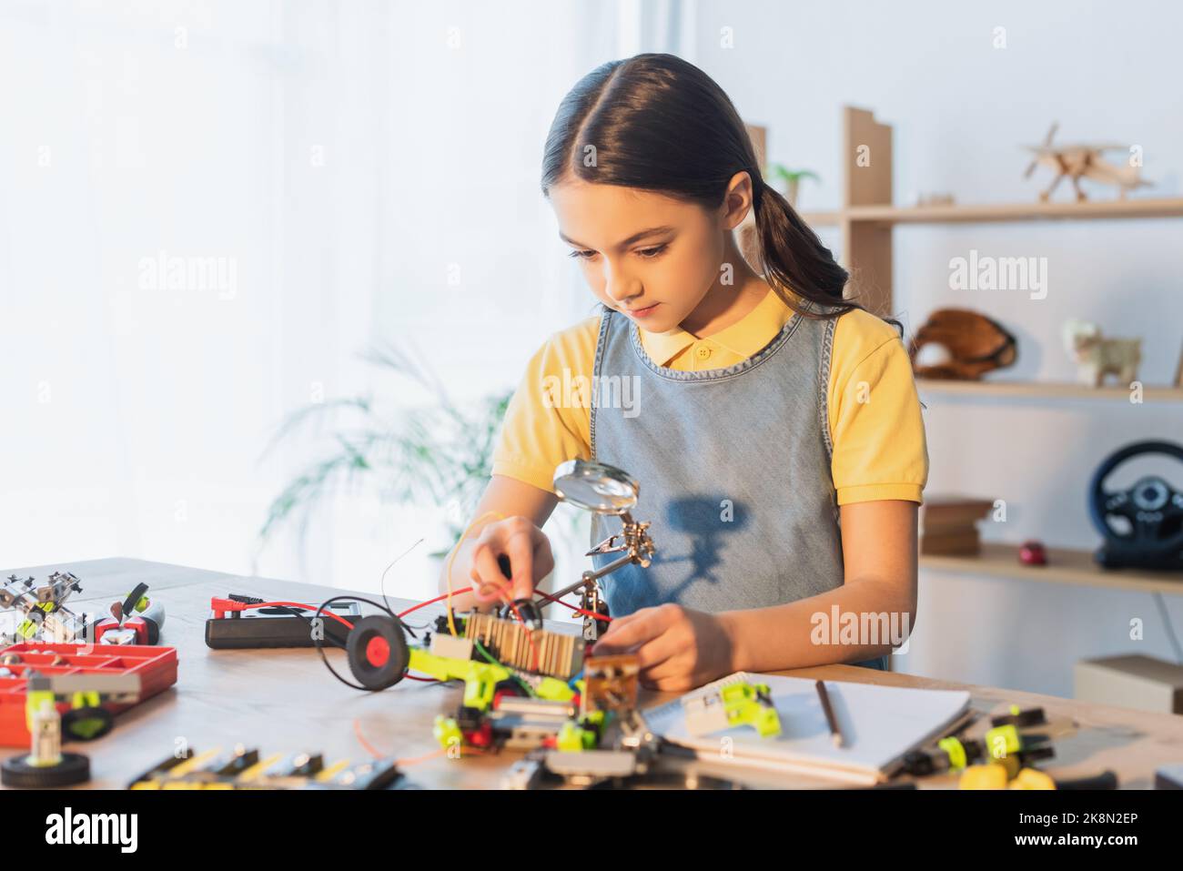 Preteen child modeling robotic model near notebook on table,stock image ...
