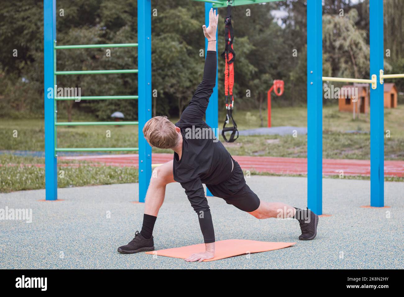 Blonde athlete warms up and stretches his body and major muscle groups ...