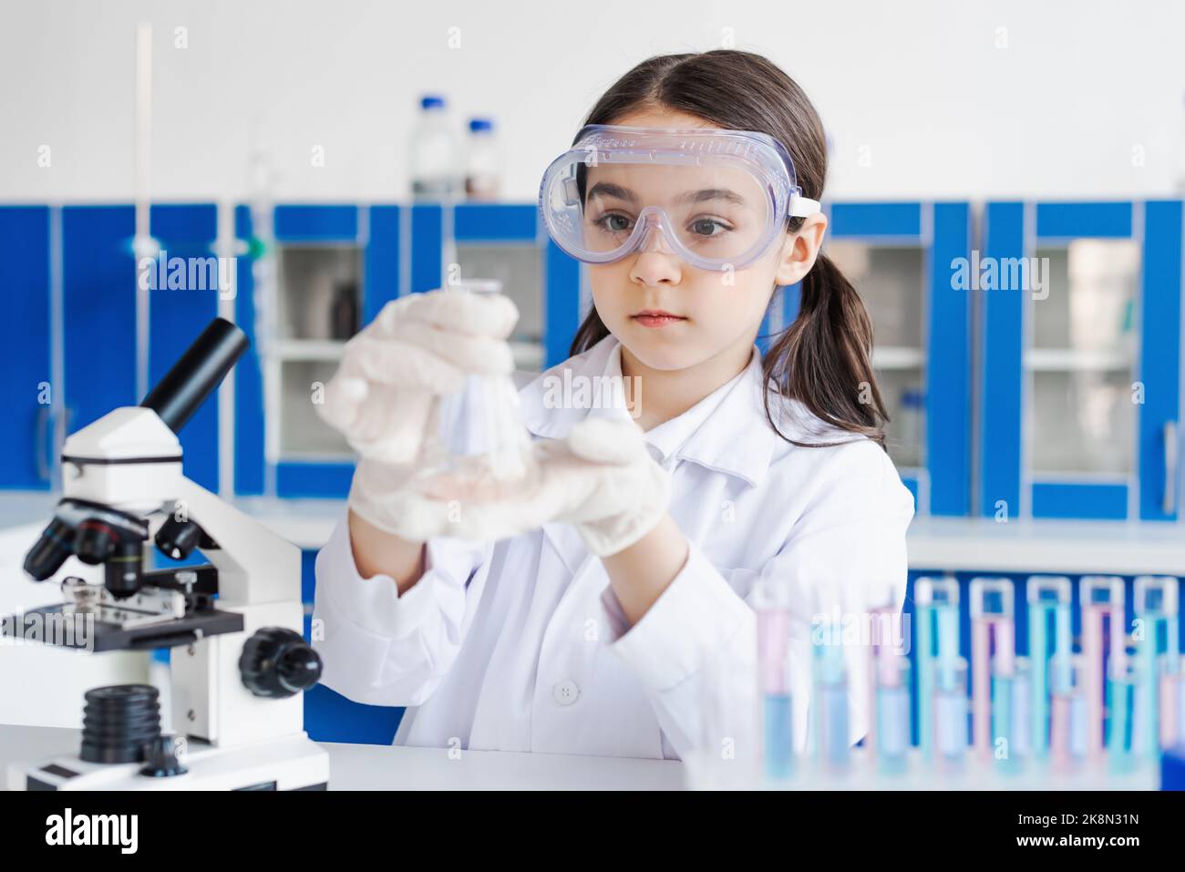 girl in goggles holding flask near microscope in laboratory,stock image ...
