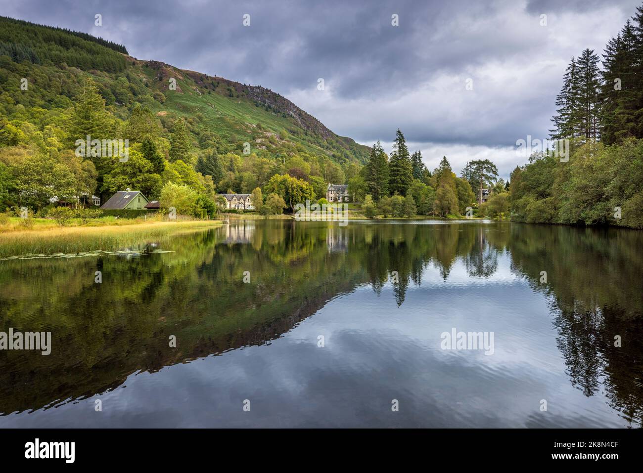 The calm waters of the eastern shore of Loch Ard in the Trossachs ...