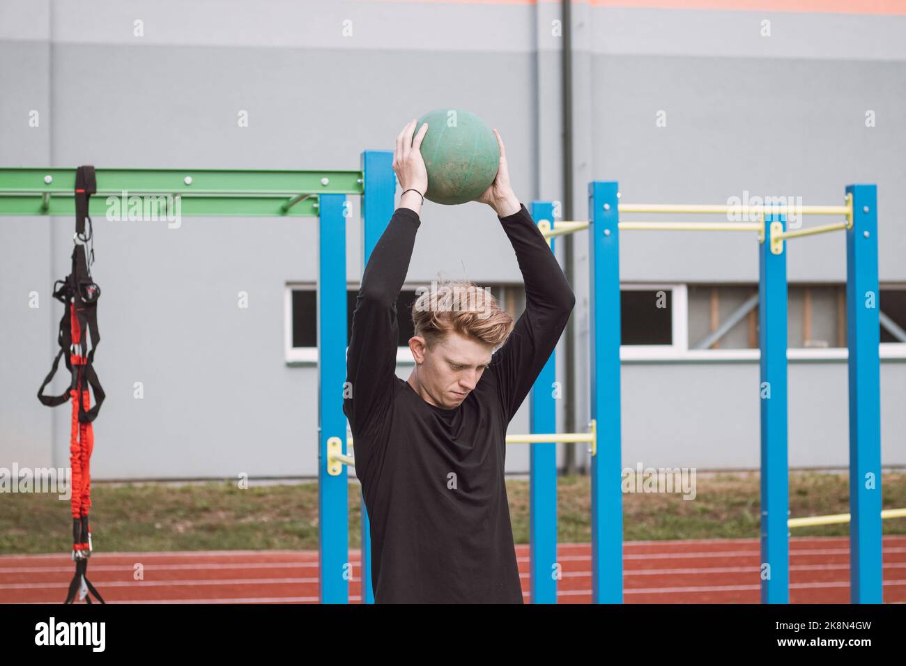 Professional athlete stands in a squatting stance holding a medicine ...