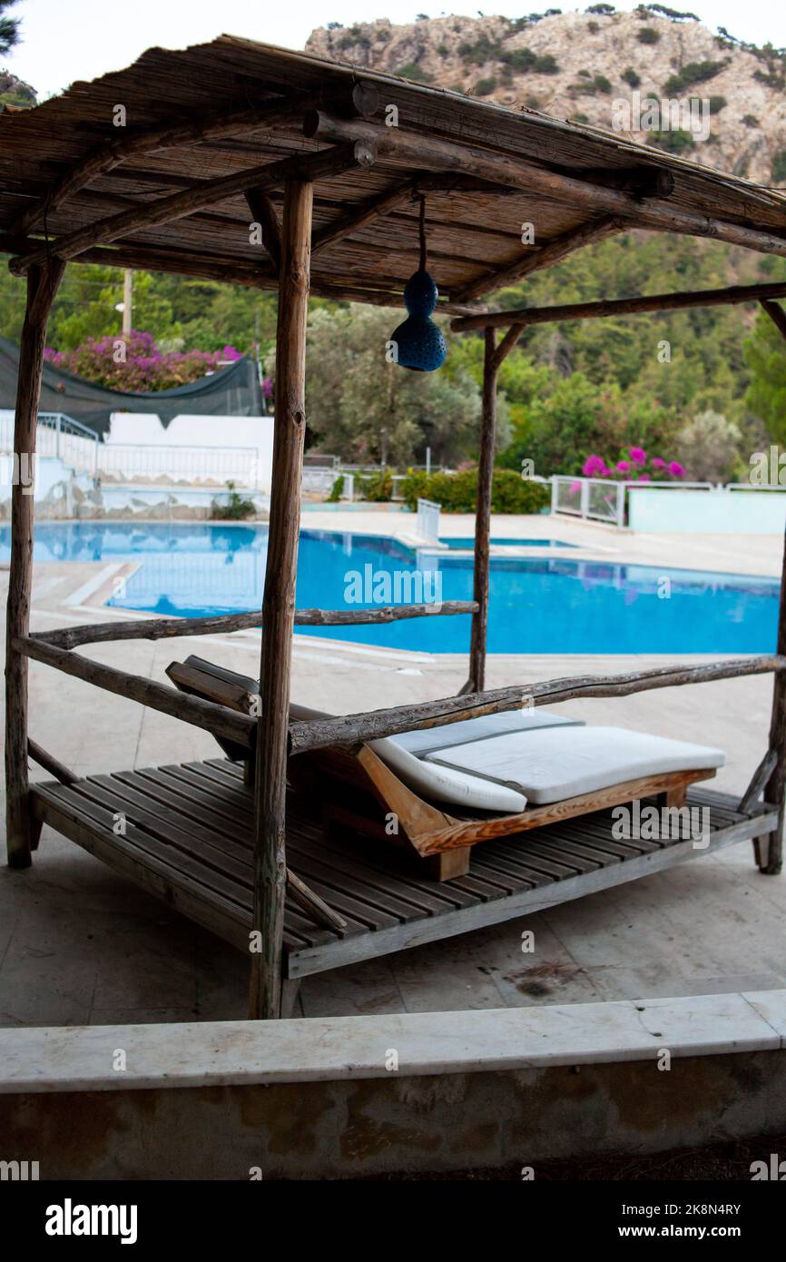 Deck chairs under a canopy stand near the swimming pool. Lounge chairs ...