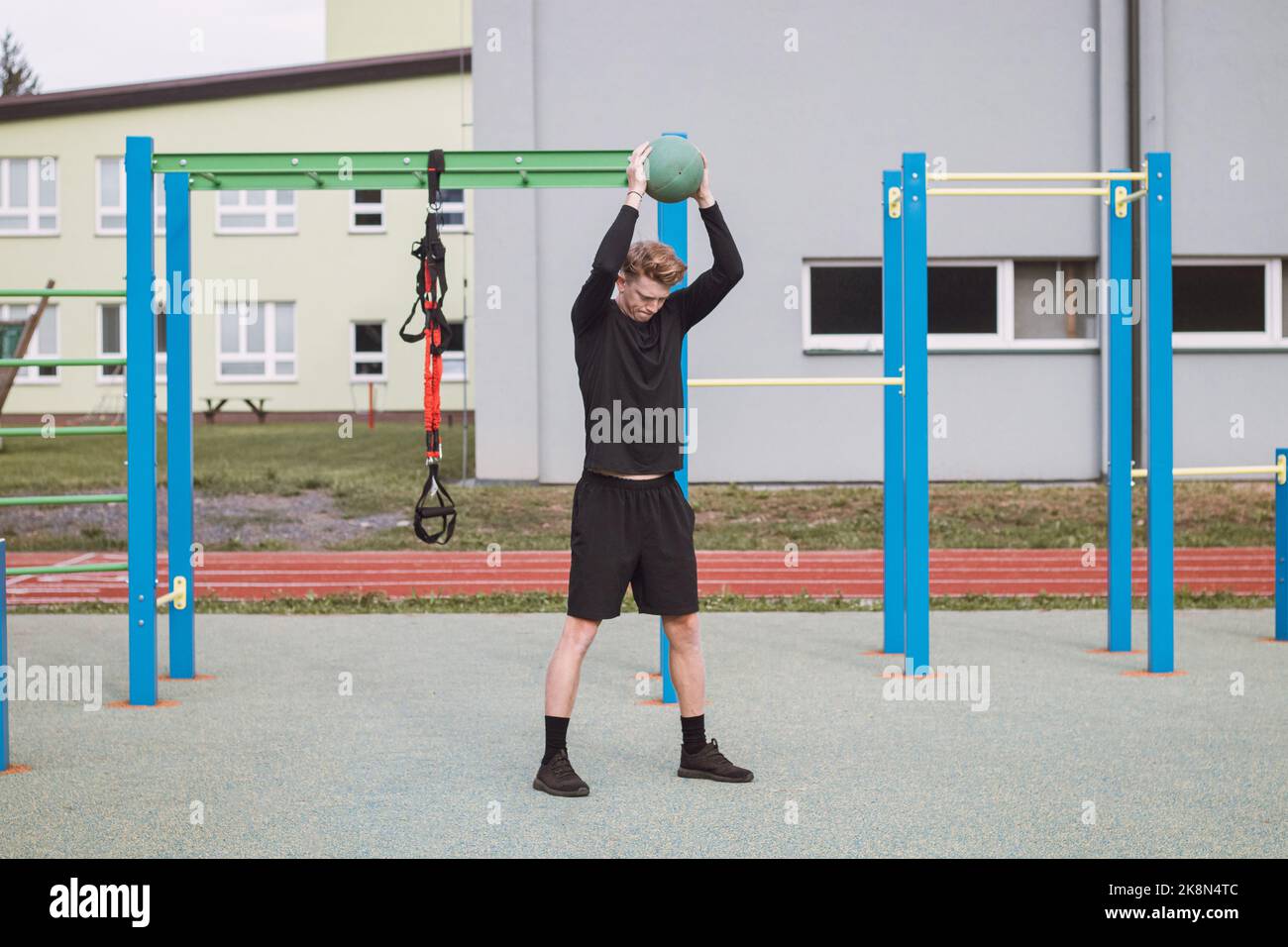 Professional athlete stands in a squatting stance holding a medicine ...