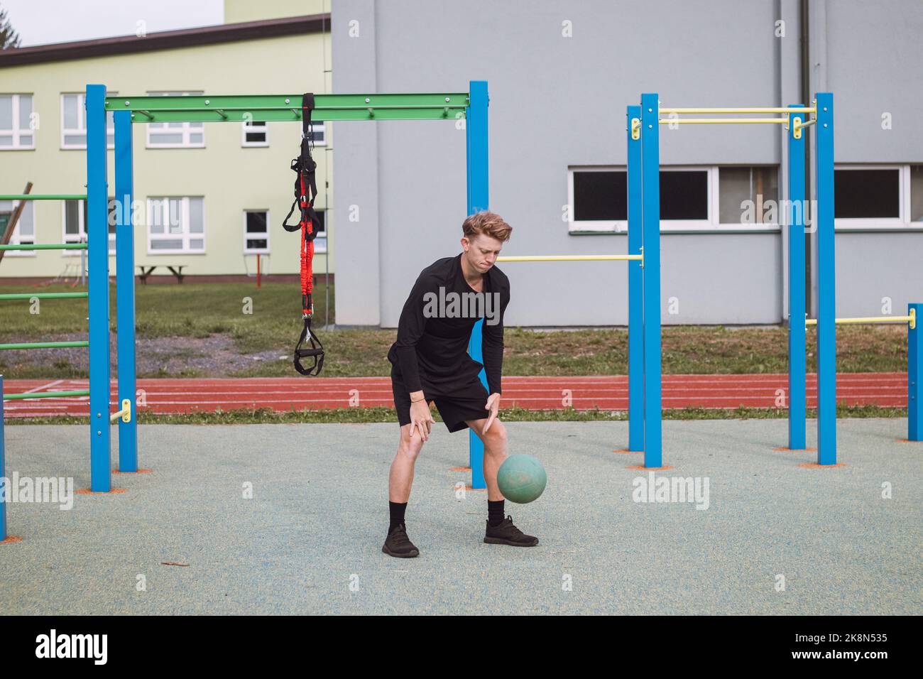 Professional athlete stands in a squatting stance holding a medicine ...