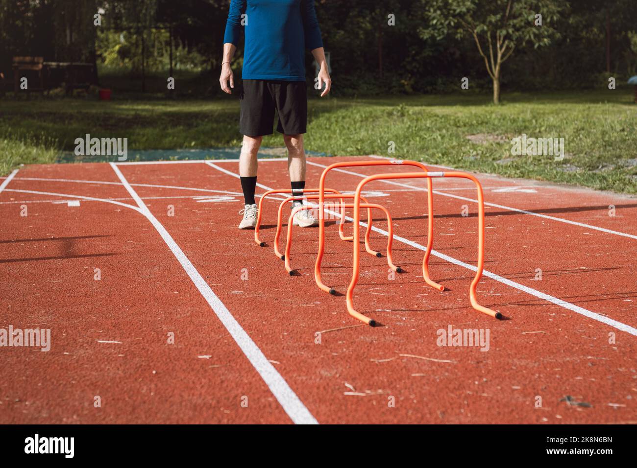 Blond boy in sportswear jumps over red obstacles to improve lower body ...