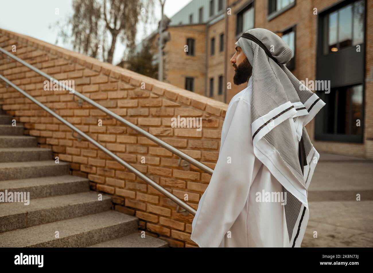 An arabian man in white traditional clothing on the stairs Stock Photo ...