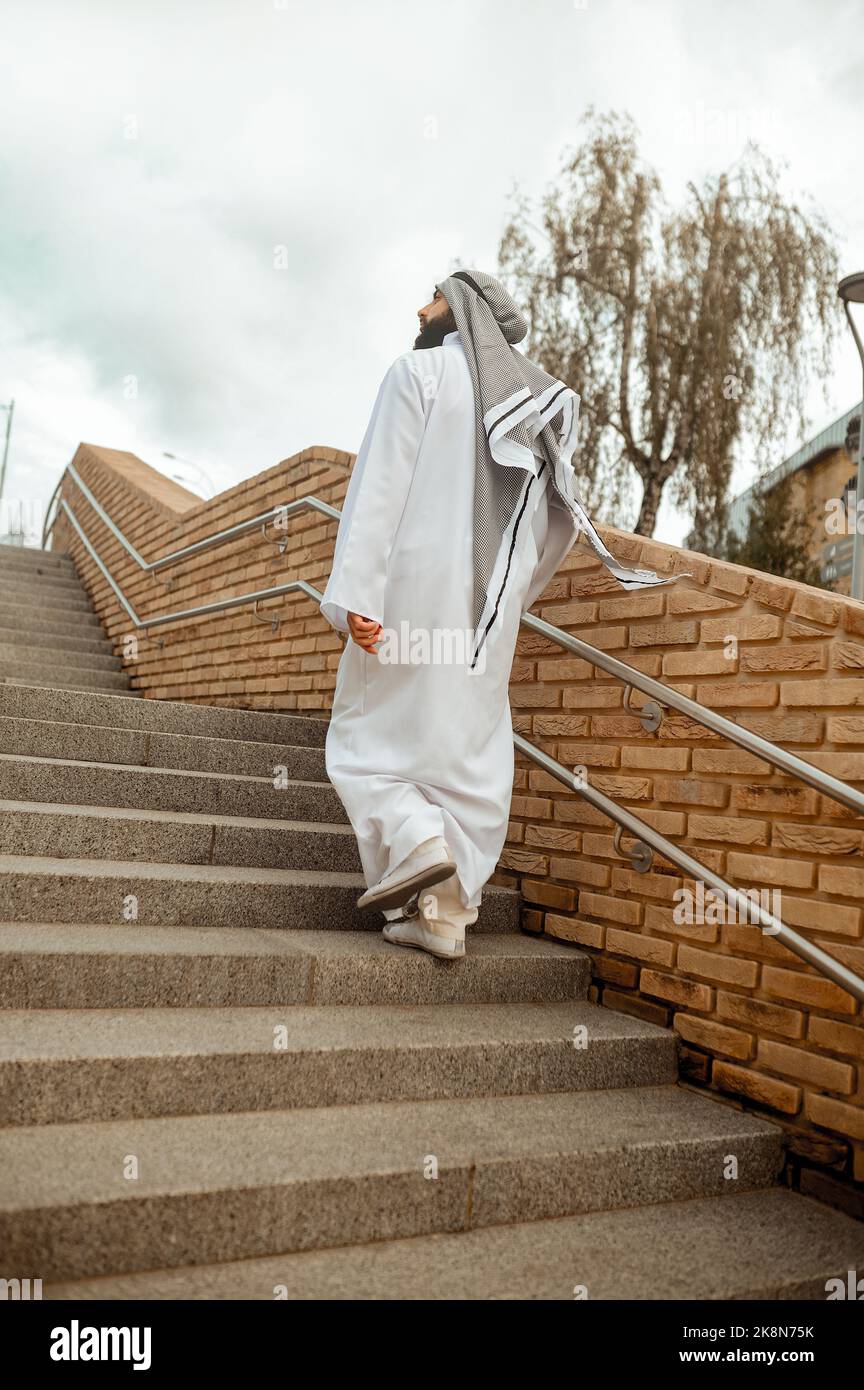 An arabian man in white traditional clothing on the stairs Stock Photo ...