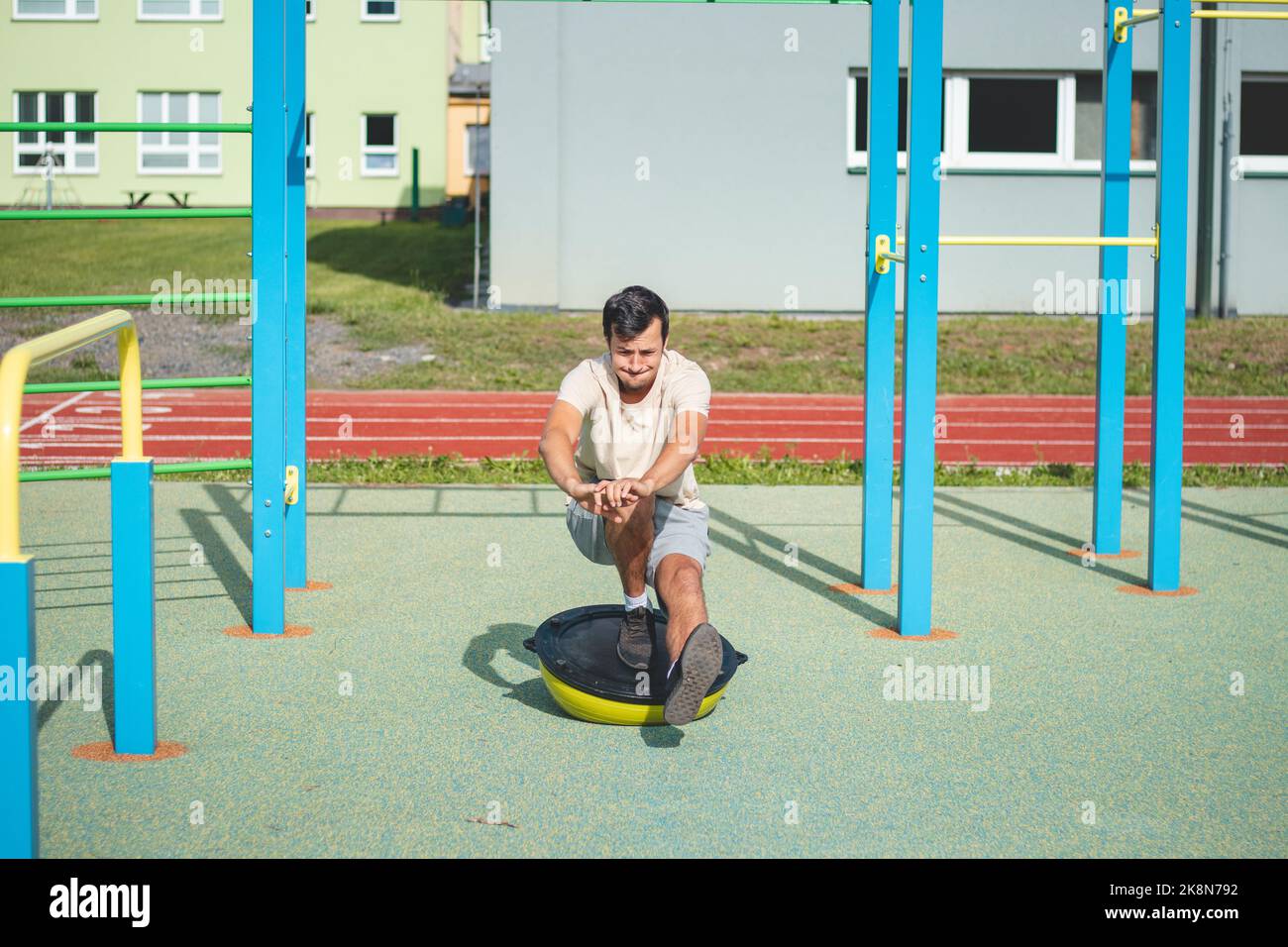 Brown-haired professional athlete does a one-legged squat on a balance ...