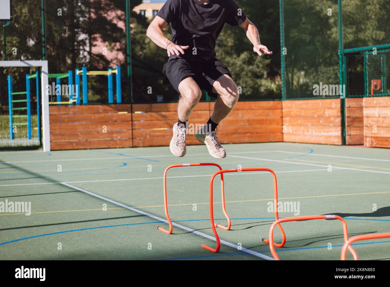Blond boy in sportswear jumps over red obstacles to improve lower body ...