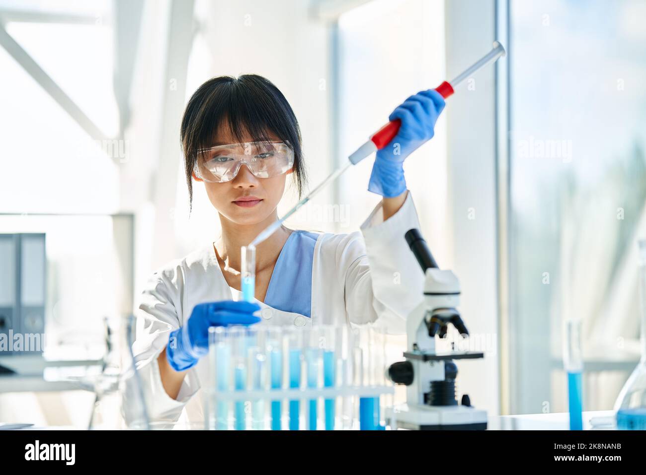 Female scientist making microbiology research using pipette, flask and ...