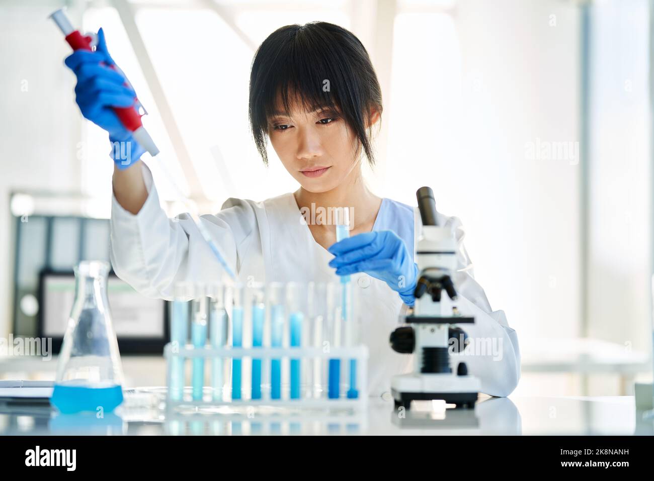Female scientist making microbiology research using pipette, flask and ...