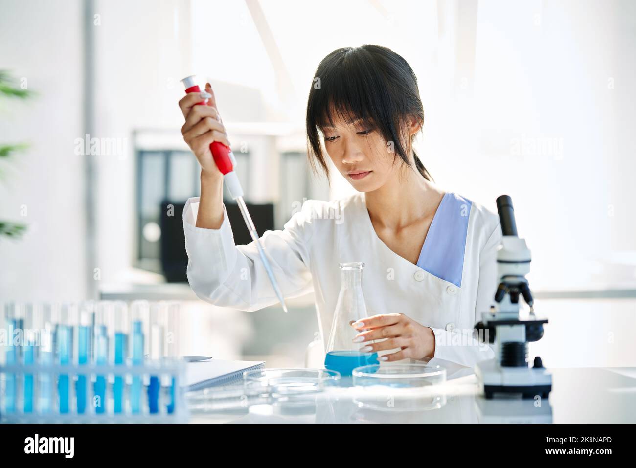 Female scientist making microbiology research using pipette, flask and ...