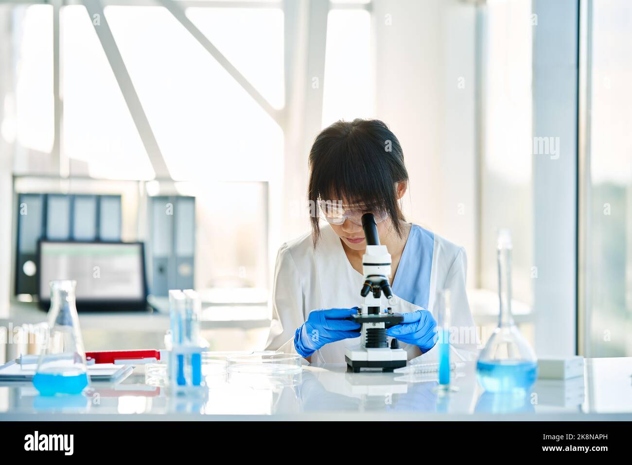 Scientist looking through a microscope working on medical research in ...