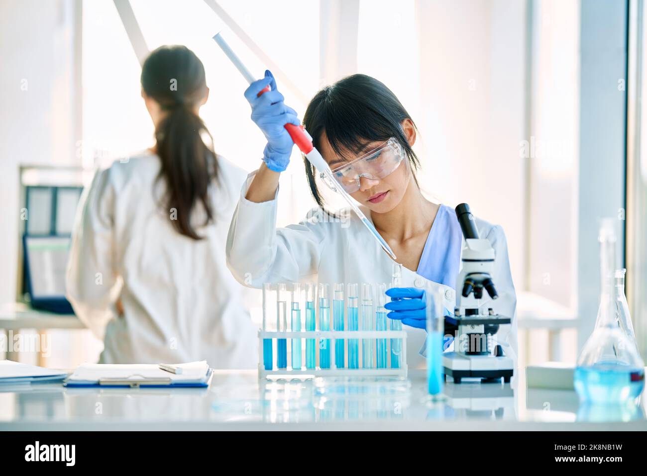 Female scientist making microbiology research using pipette, flask and ...