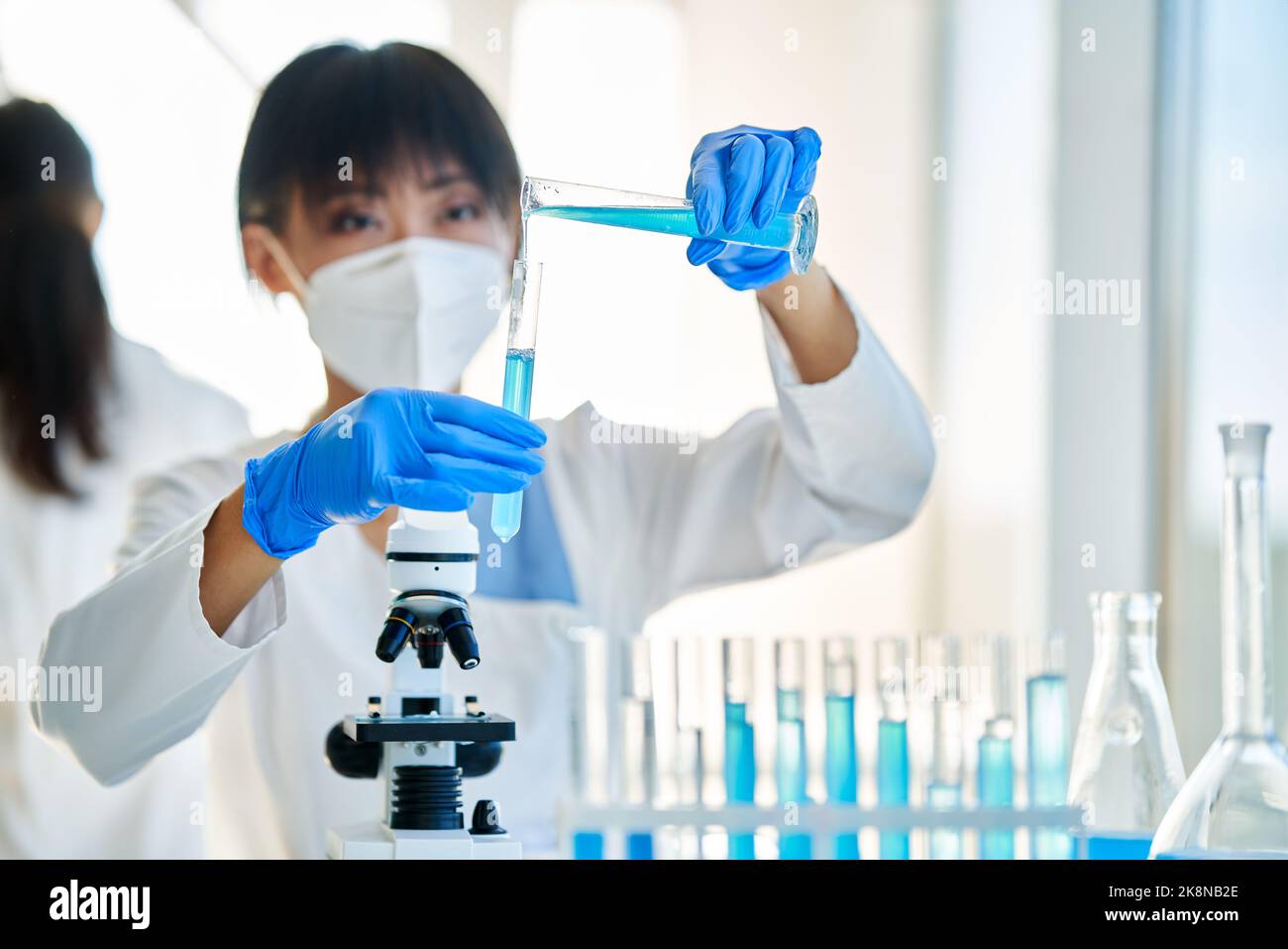 Female scientist making research pouring reagent into test tubes ...