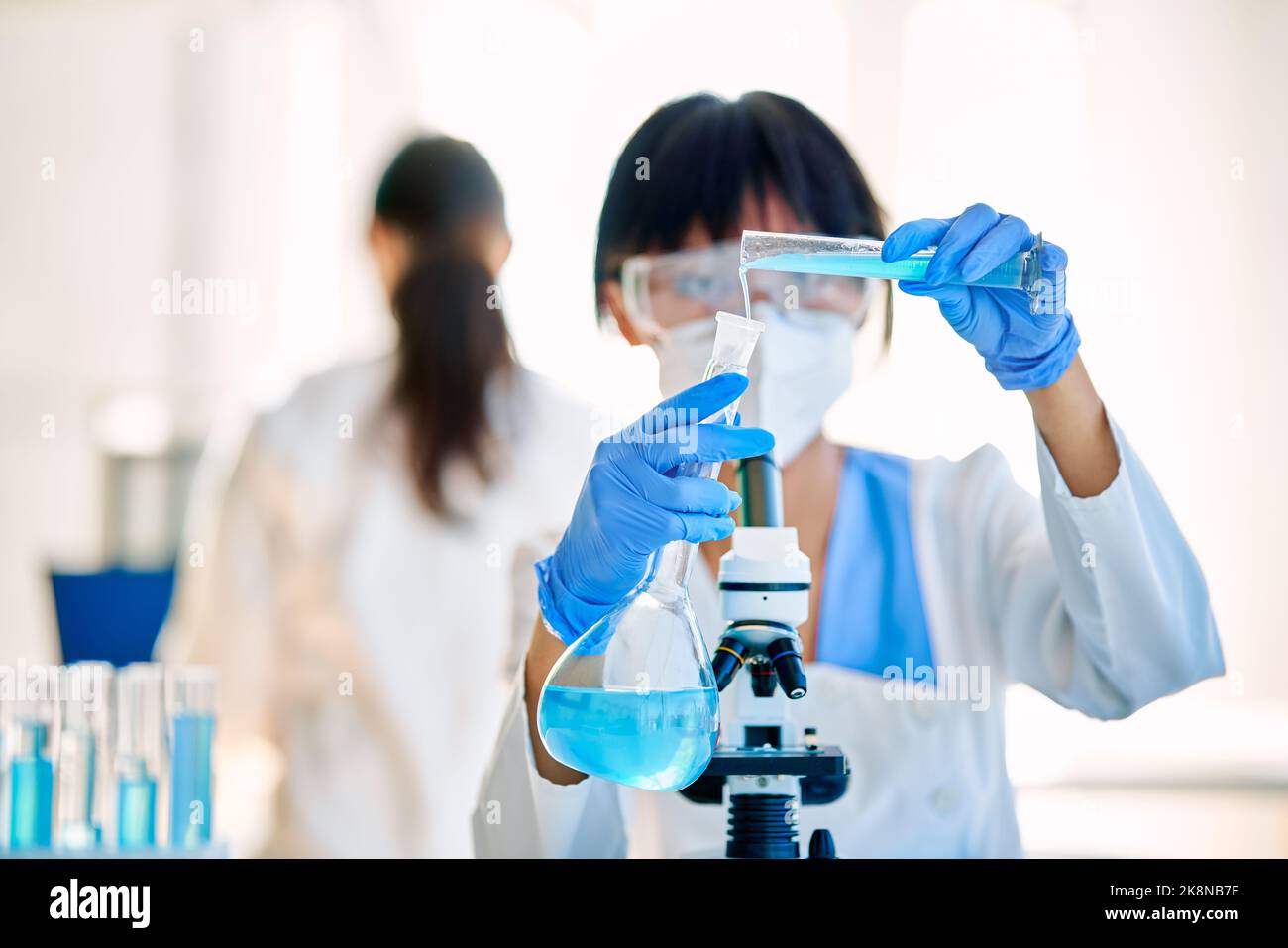 Female scientist making research pouring reagent into test tubes ...