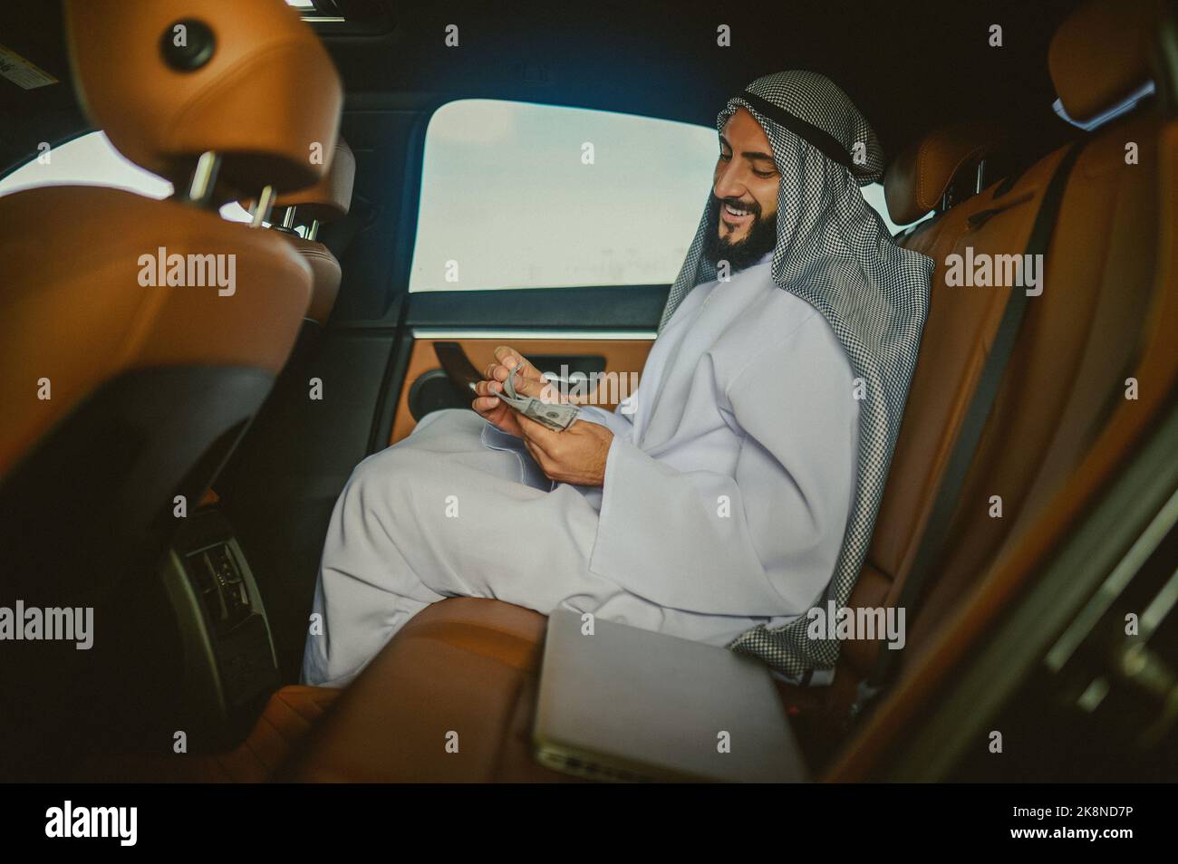 Saudi man in a traditional clothing in a car holding money Stock Photo ...