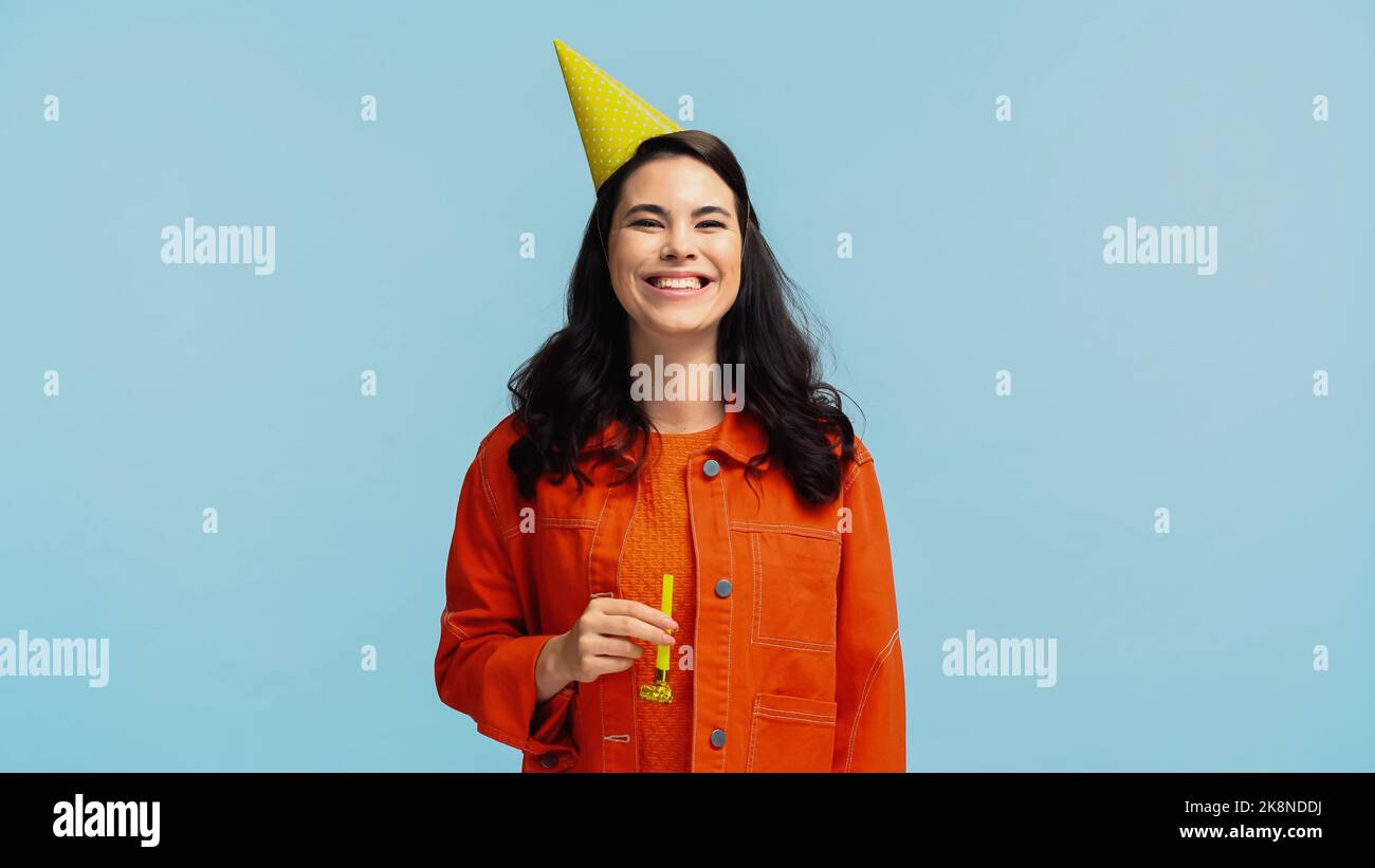cheerful young woman in orange jacket and party cap holding festive ...