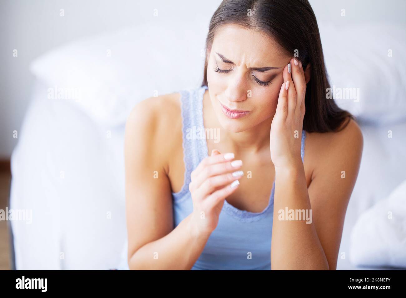 Pain head. Pretty Sad Woman With a Strong Headache in Her Home sitting on the Bed Stock Photo ...
